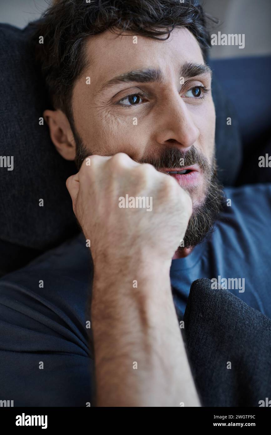 stressed desperate man with beard in casual outfit lying with hands on ...