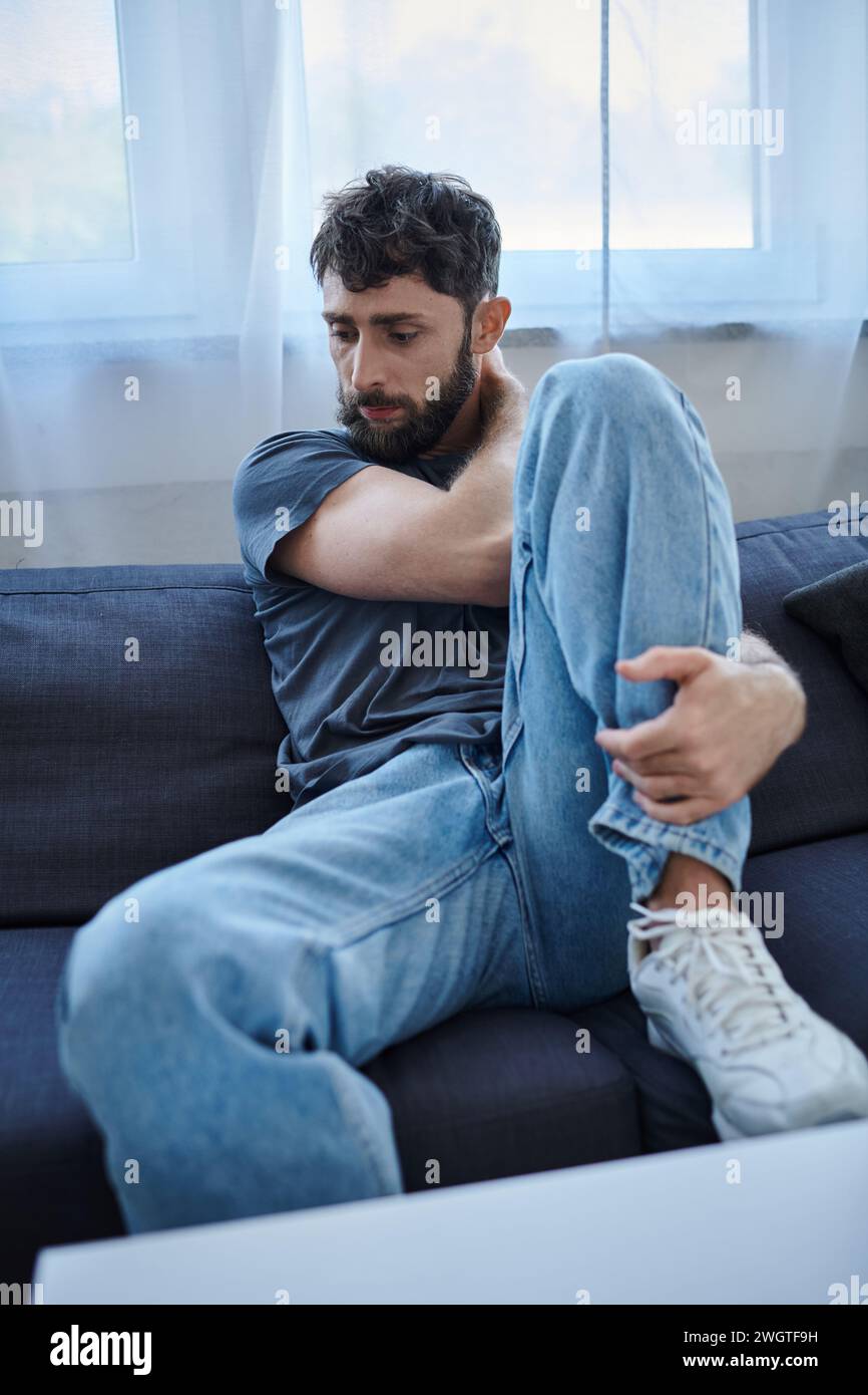 traumatized anxious man in casual clothes sitting on sofa during ...