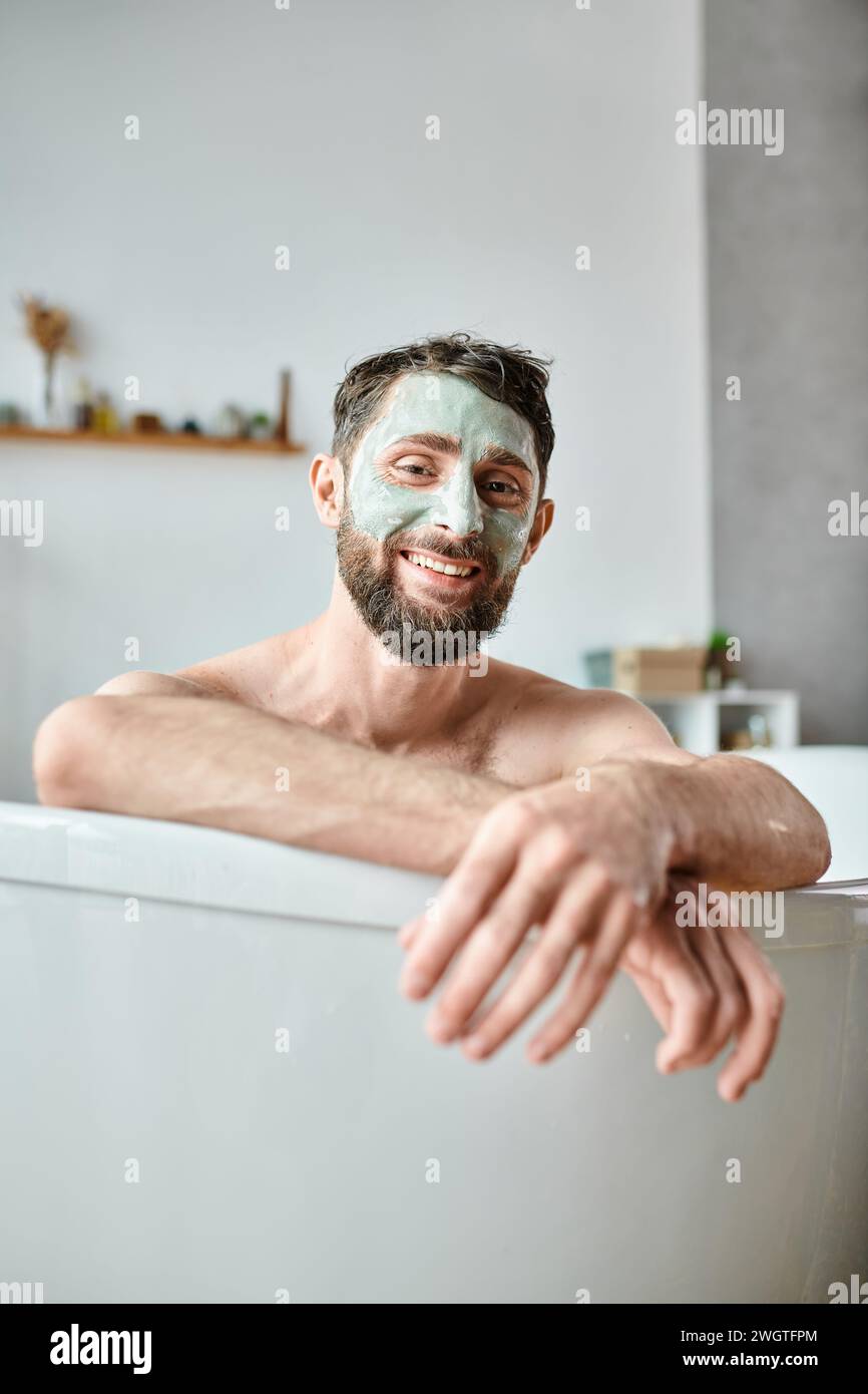 joyful attractive man with beard and face mask chilling in his bathtub ...