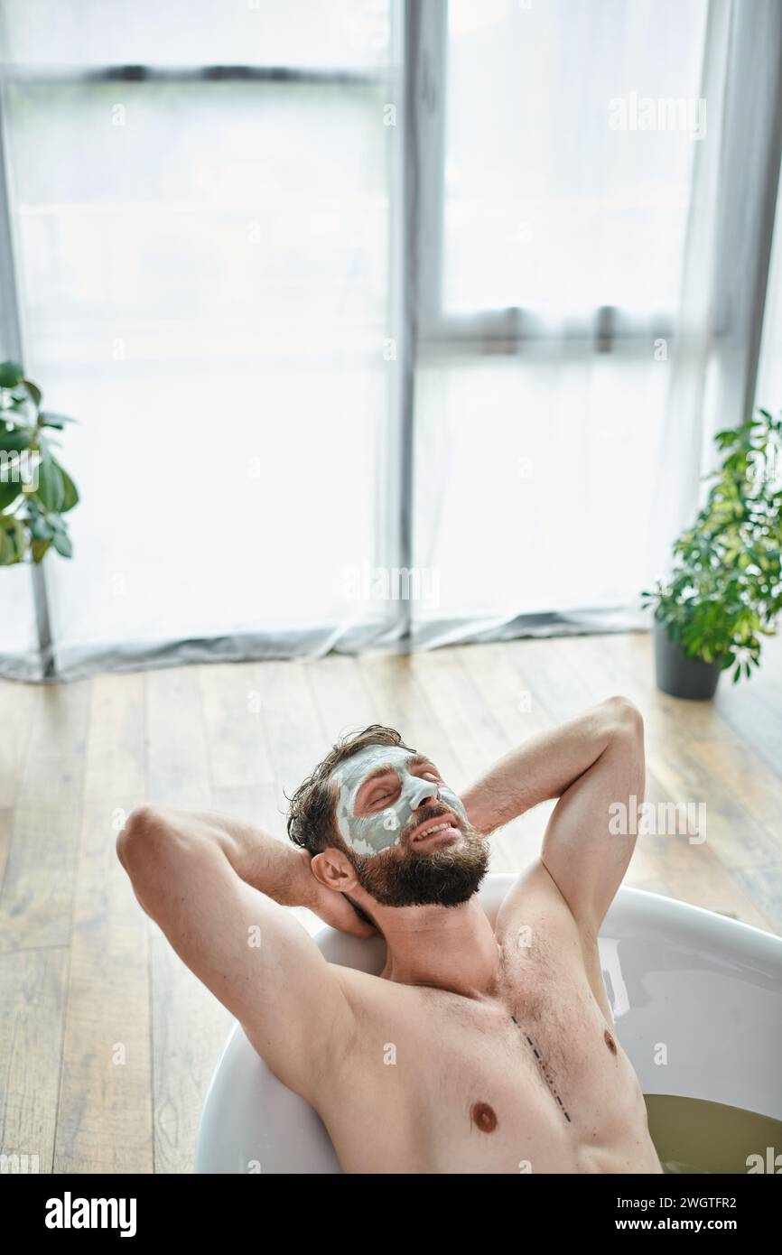 good looking jolly man with beard and face mask chilling in his bathtub ...