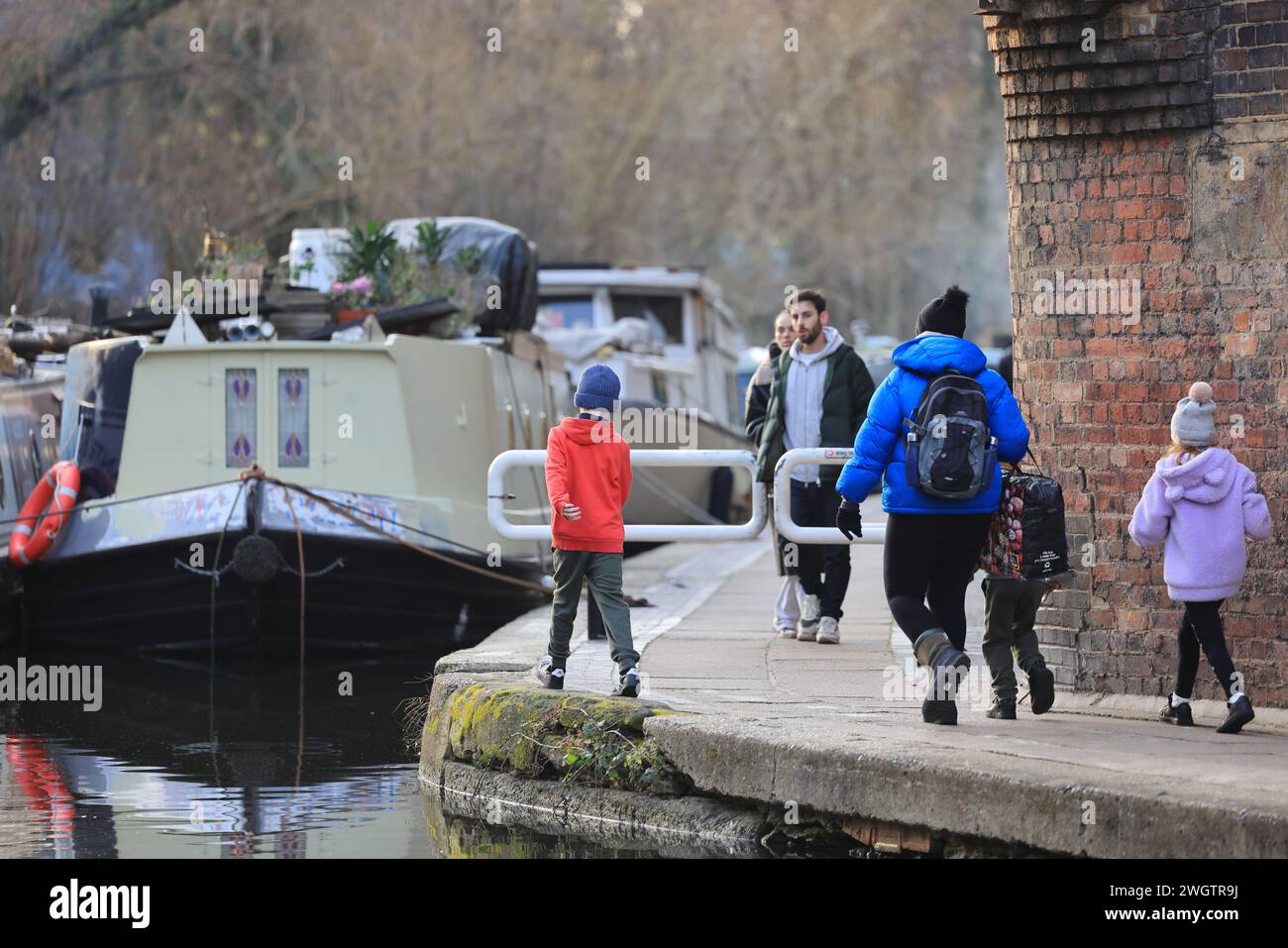 Walking along the towpath in winter, by the barges of Regents Canal at ...