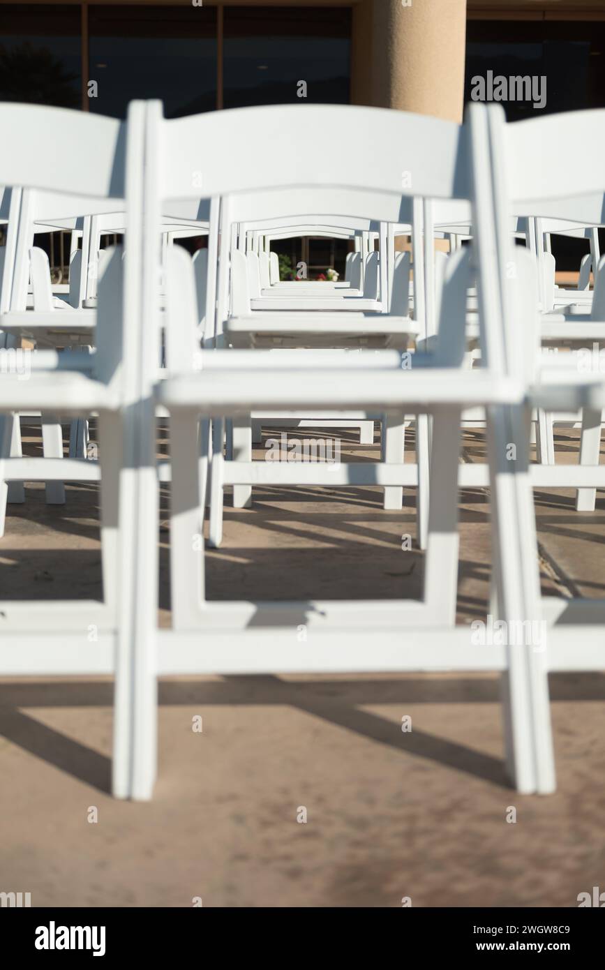Rows of white folding chairs arranged outdoors next to columns outside ...