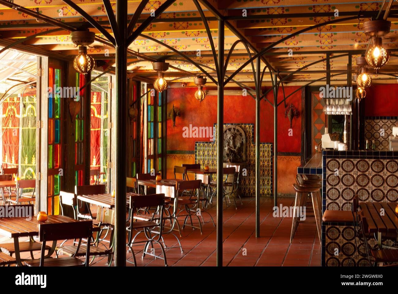 Colorful stained glass walls surround tables with numerous chairs in a ...