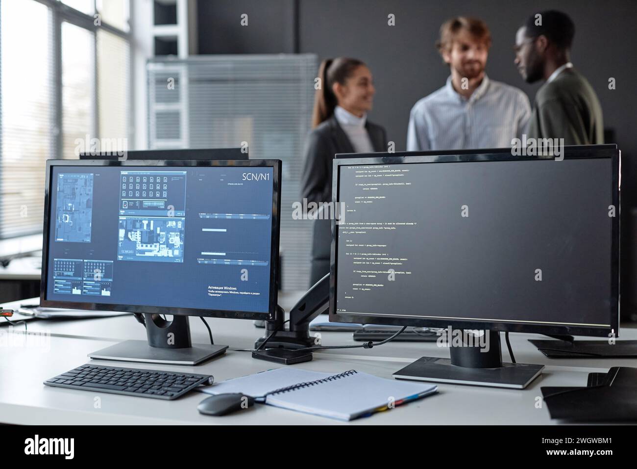 PC computers with code lines and blue data on screen at desk in ...