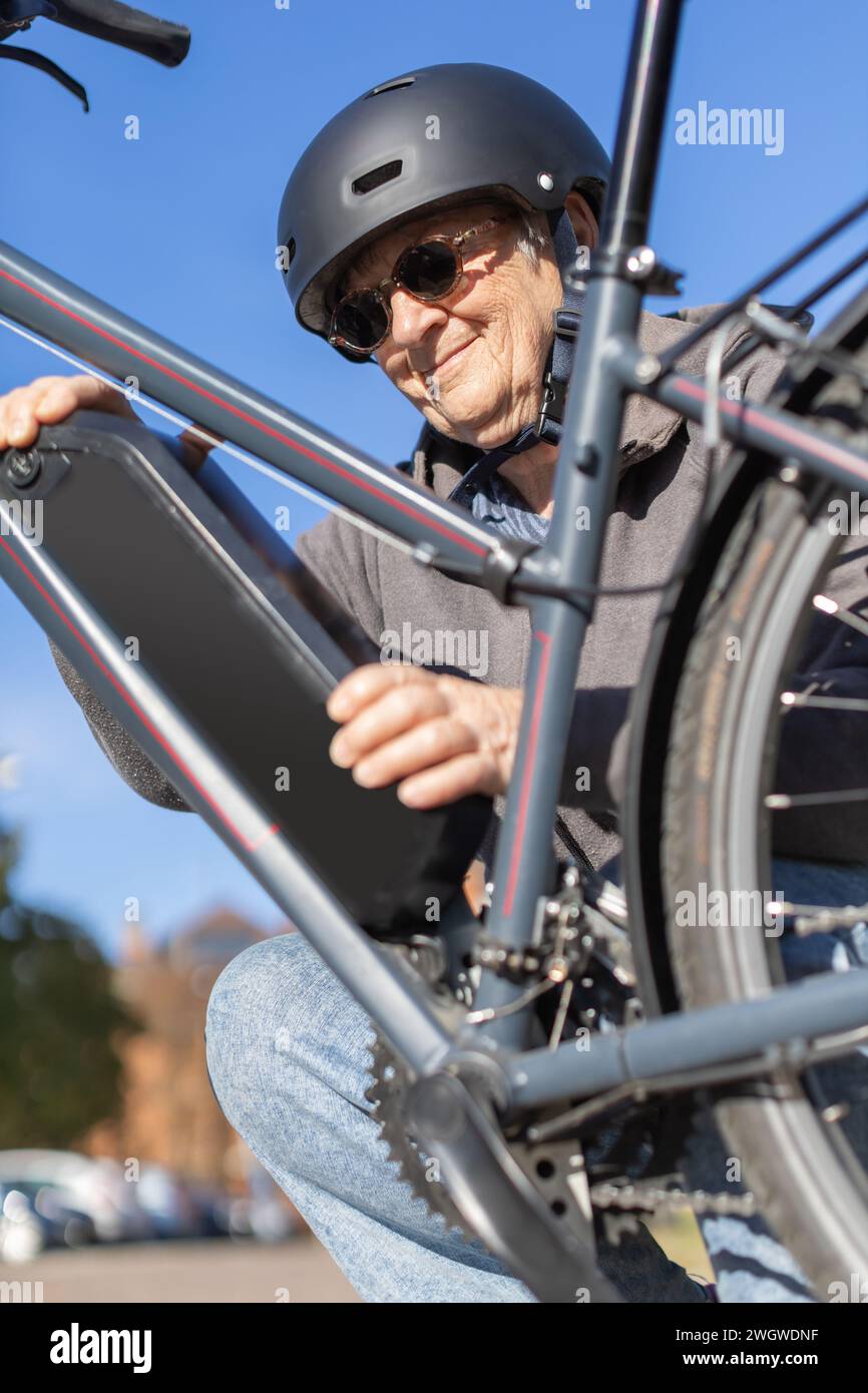 elderly woman changing battery on electric bicycle Stock Photo - Alamy