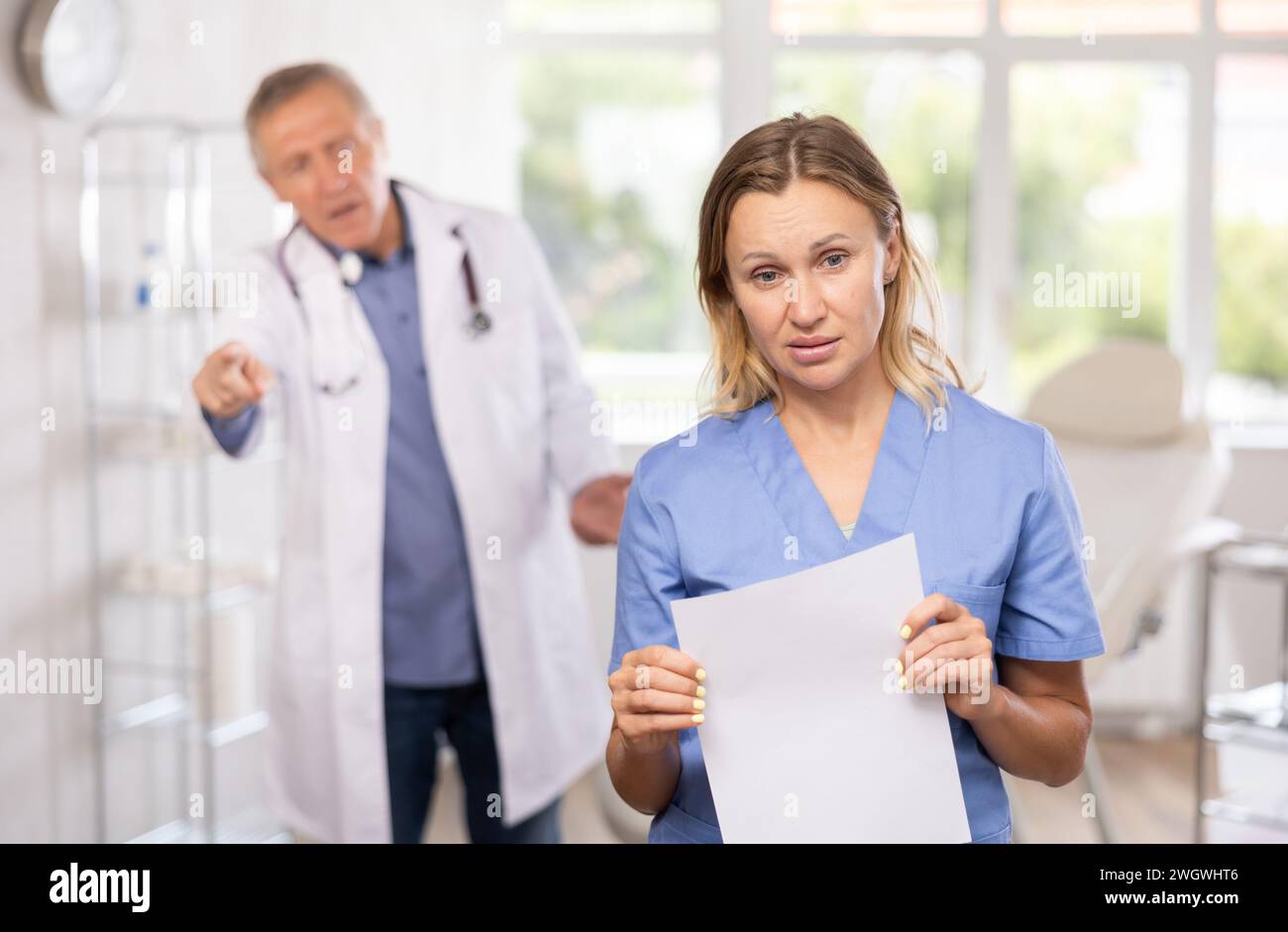 Upset middle-aged nurse standing with her back to angry doctor Stock ...