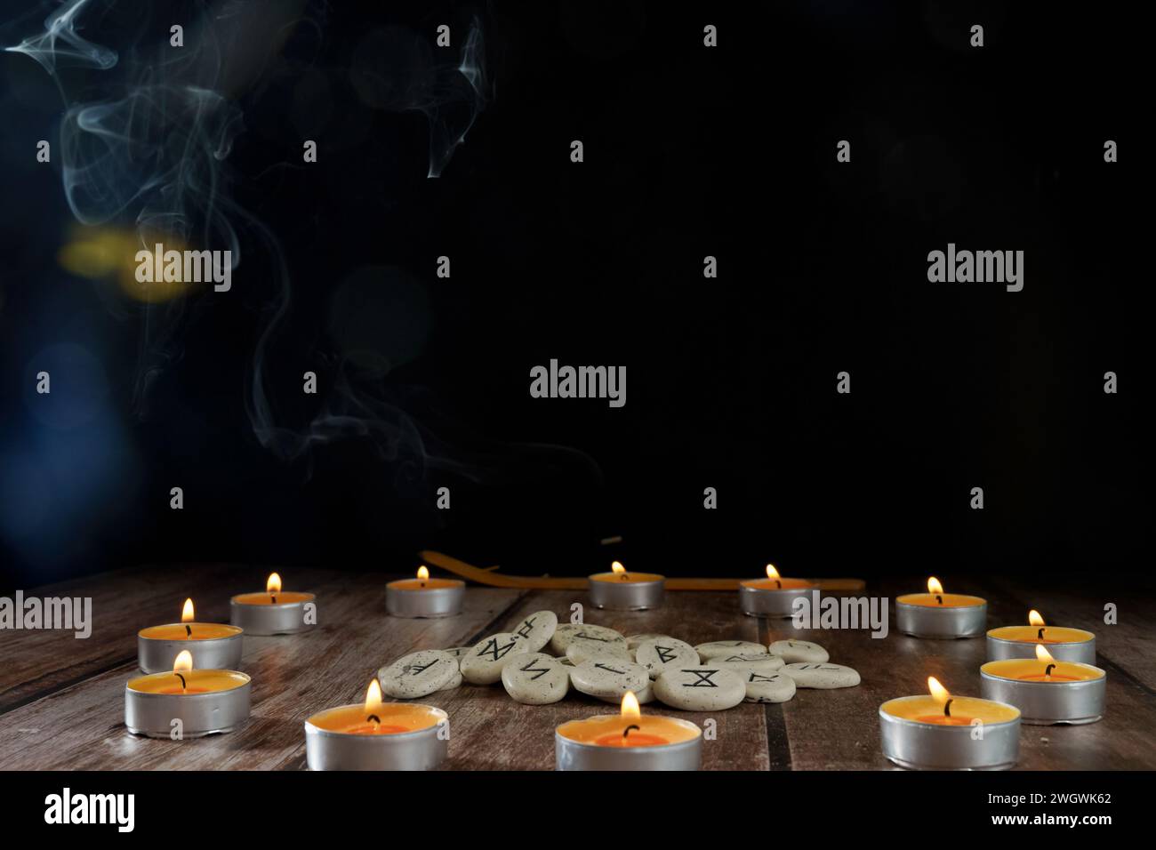 Circle of lighted candles with stone runes in the center, on the black ...