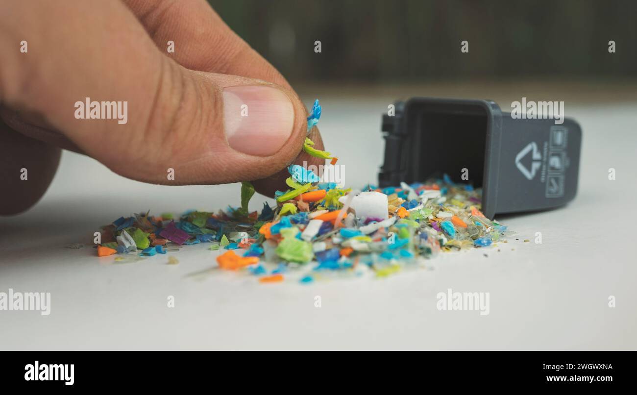 Macro shot of fingers taking particles of micro plastics from a mini ...