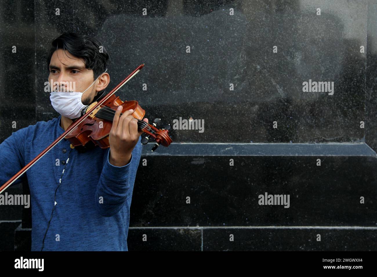 Latin man with protection mask playing musical instrument violin in the ...