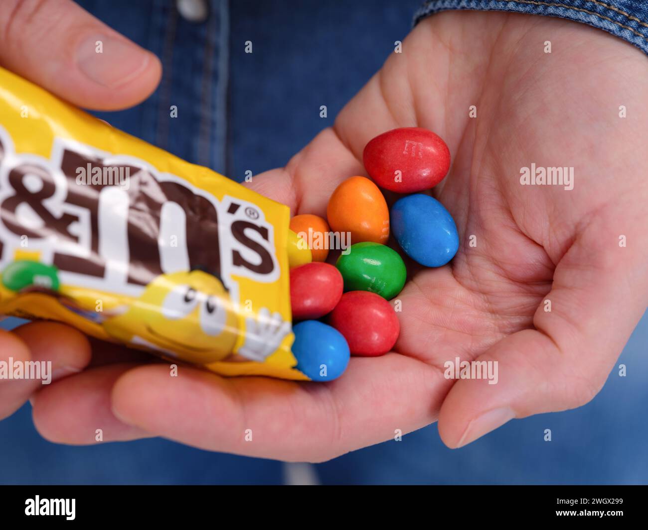 Tambov, Russian Federation - January 23, 2024 A woman pouring M&Ms in ...