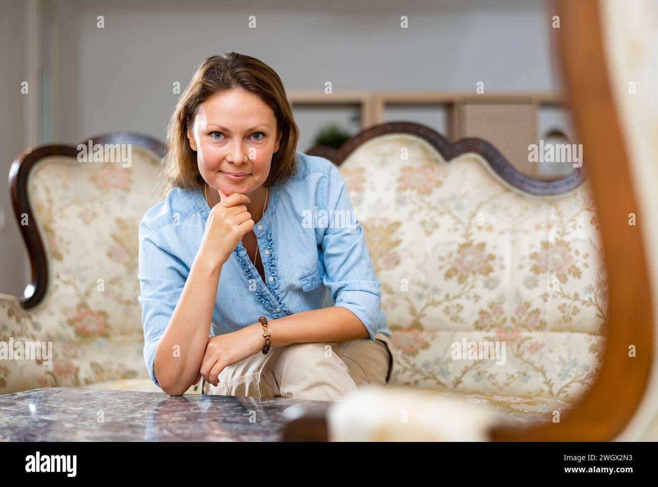 Positive lady in casual clothes sitting on the couch while resting in ...