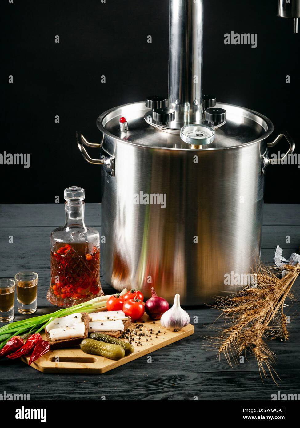 Moonshine still on a black wooden background. Alcohol in a glass ...