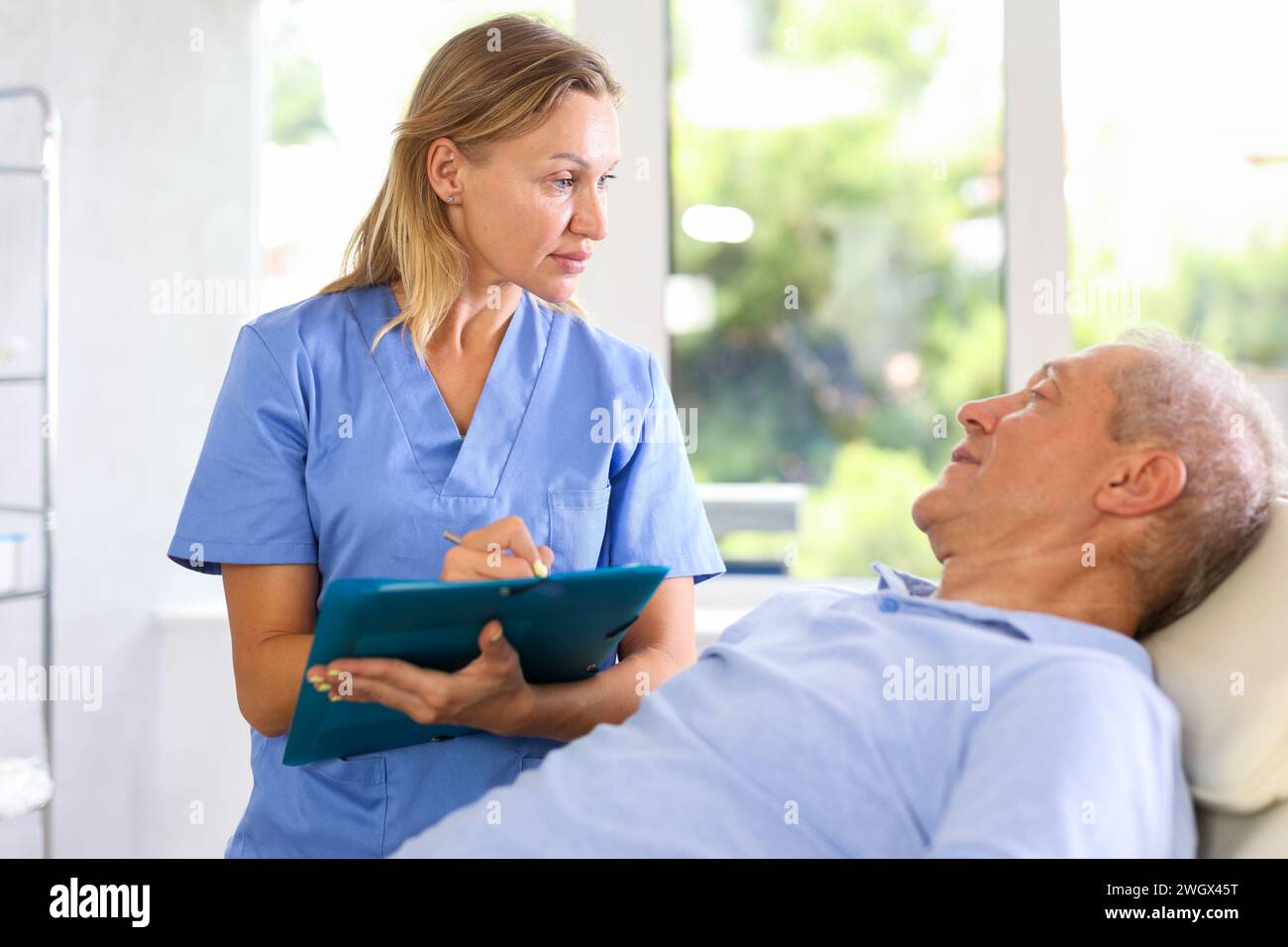 Female doctor gathering medical information of senior male patient ...