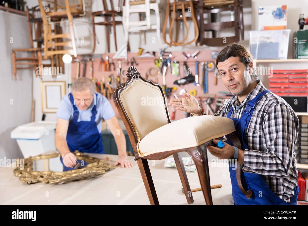 Furniture restorer in process of renovation vintage chair in workshop ...