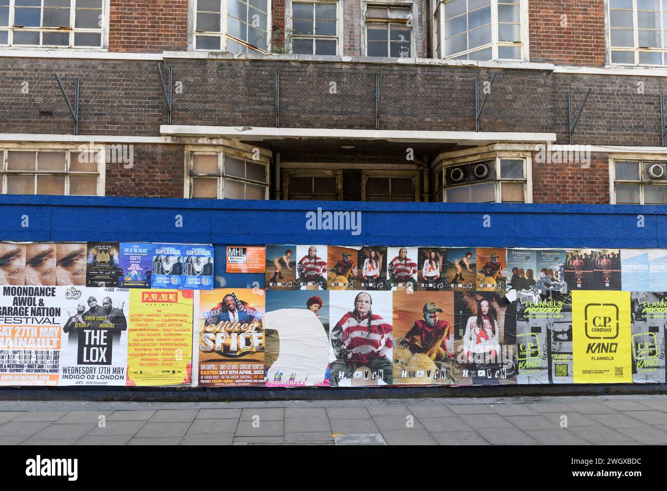 A fence around an empty building covered with fly posters, New Road ...