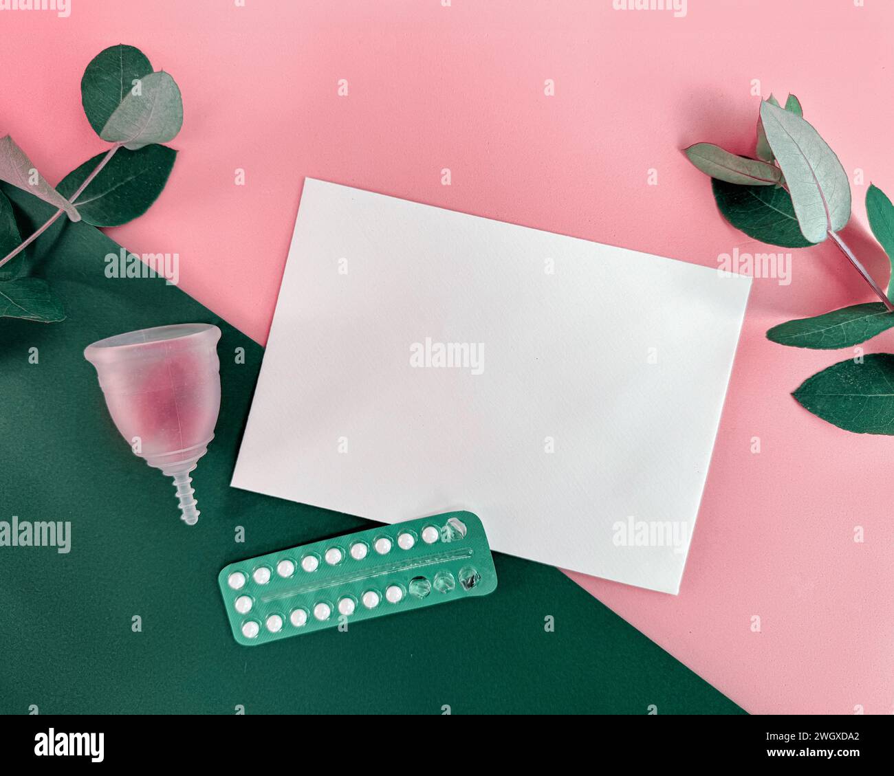Menstrual cup and contraceptive pills on pink and green background with ...