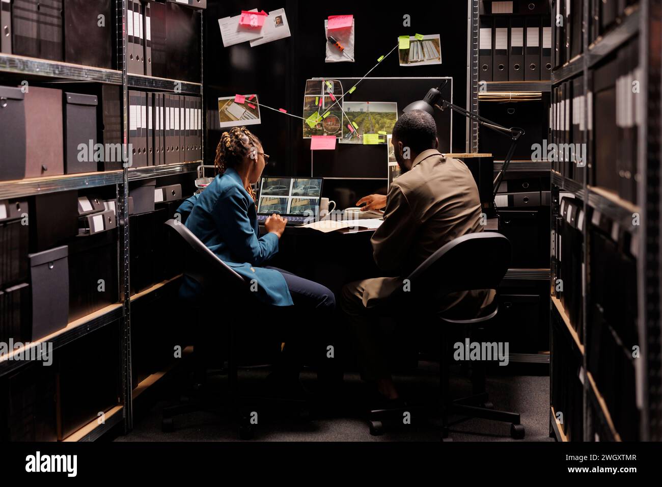 Private detectives looking at surveillance photos on laptop and ...
