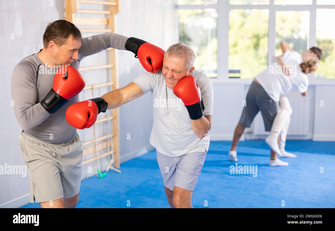 Boxing fight - elderly man learning to box in sparring with trainer in ...