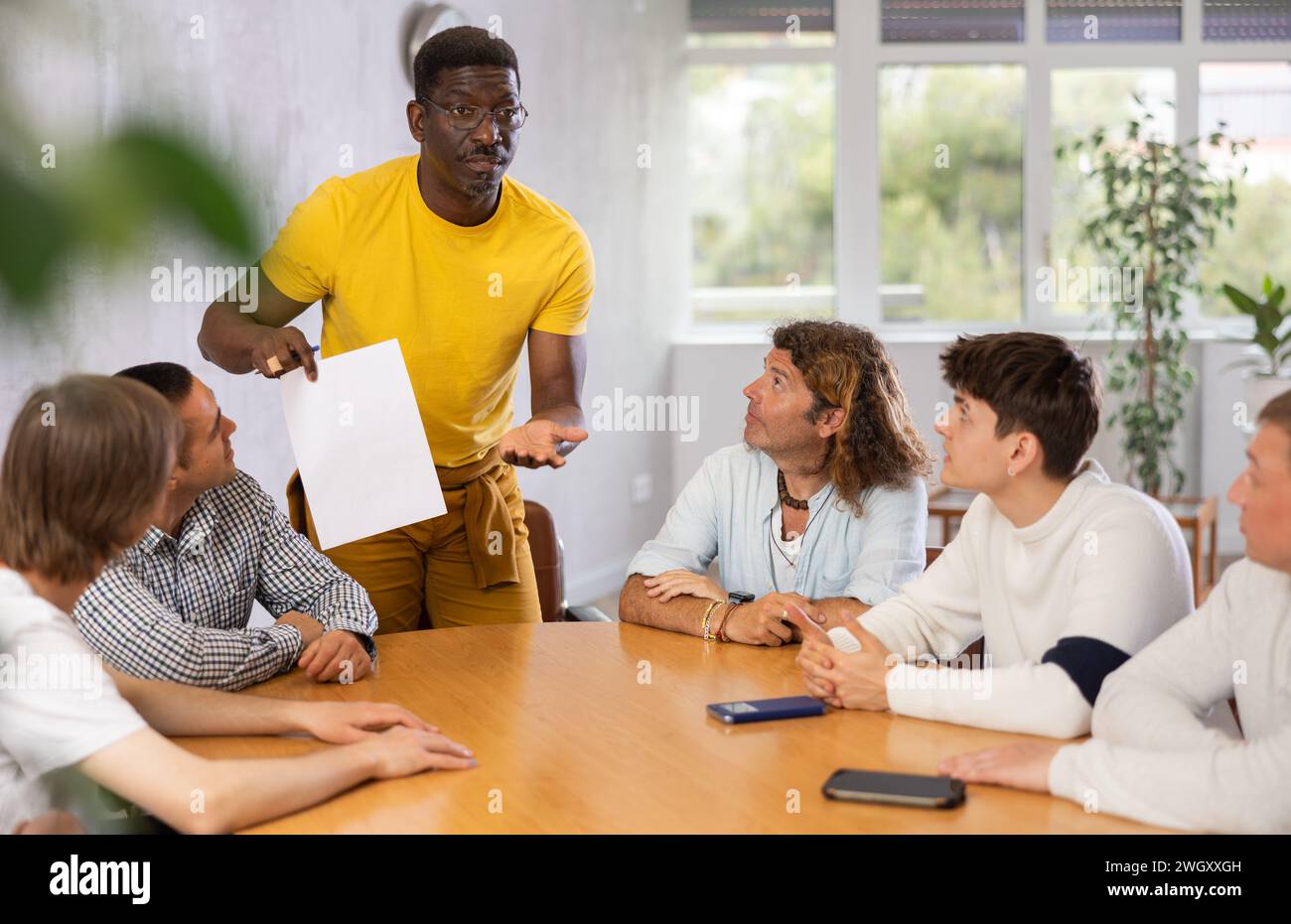 African American tutor holding paper conducting lesson for male group ...
