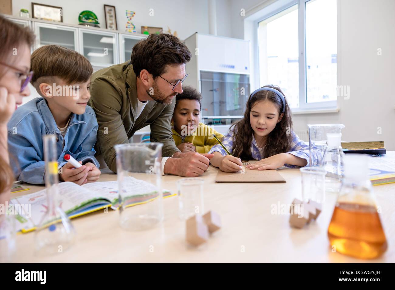 Teacher and children in a classroom, exploring a new topic in chemistry ...