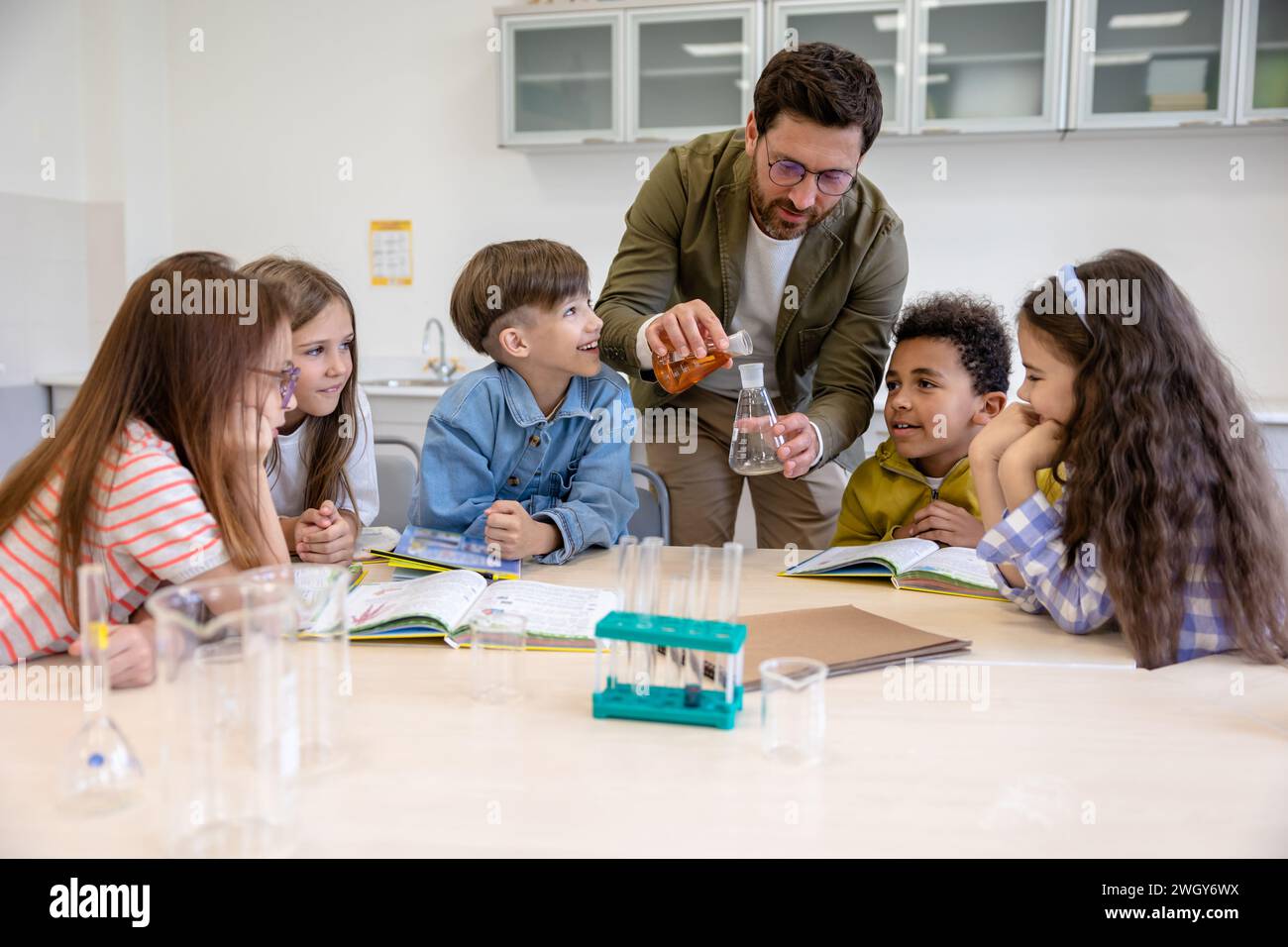 Teacher and children in a classroom, exploring a new topic in chemistry ...