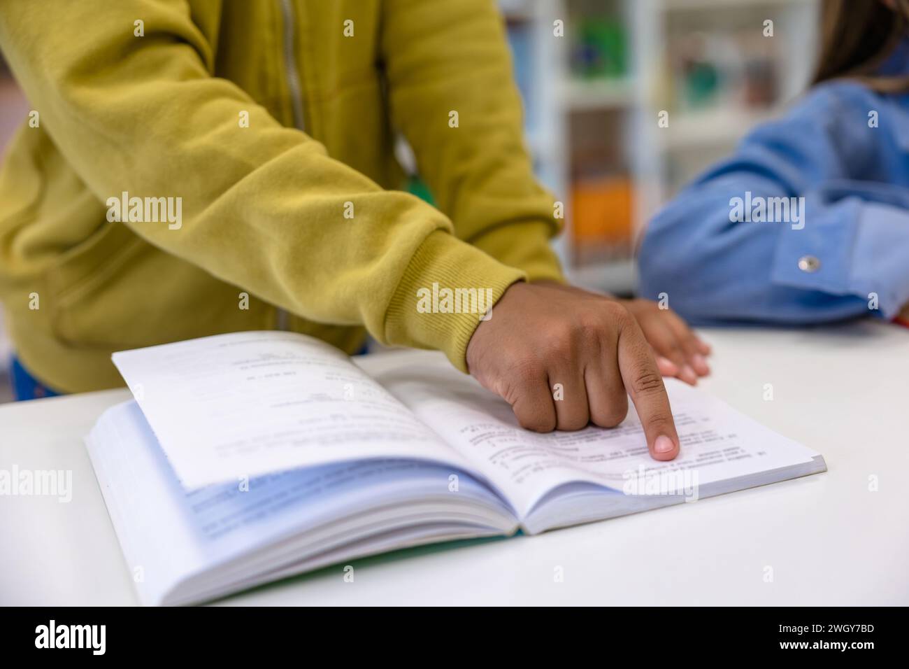 Little boy reading book in school library Stock Photo - Alamy