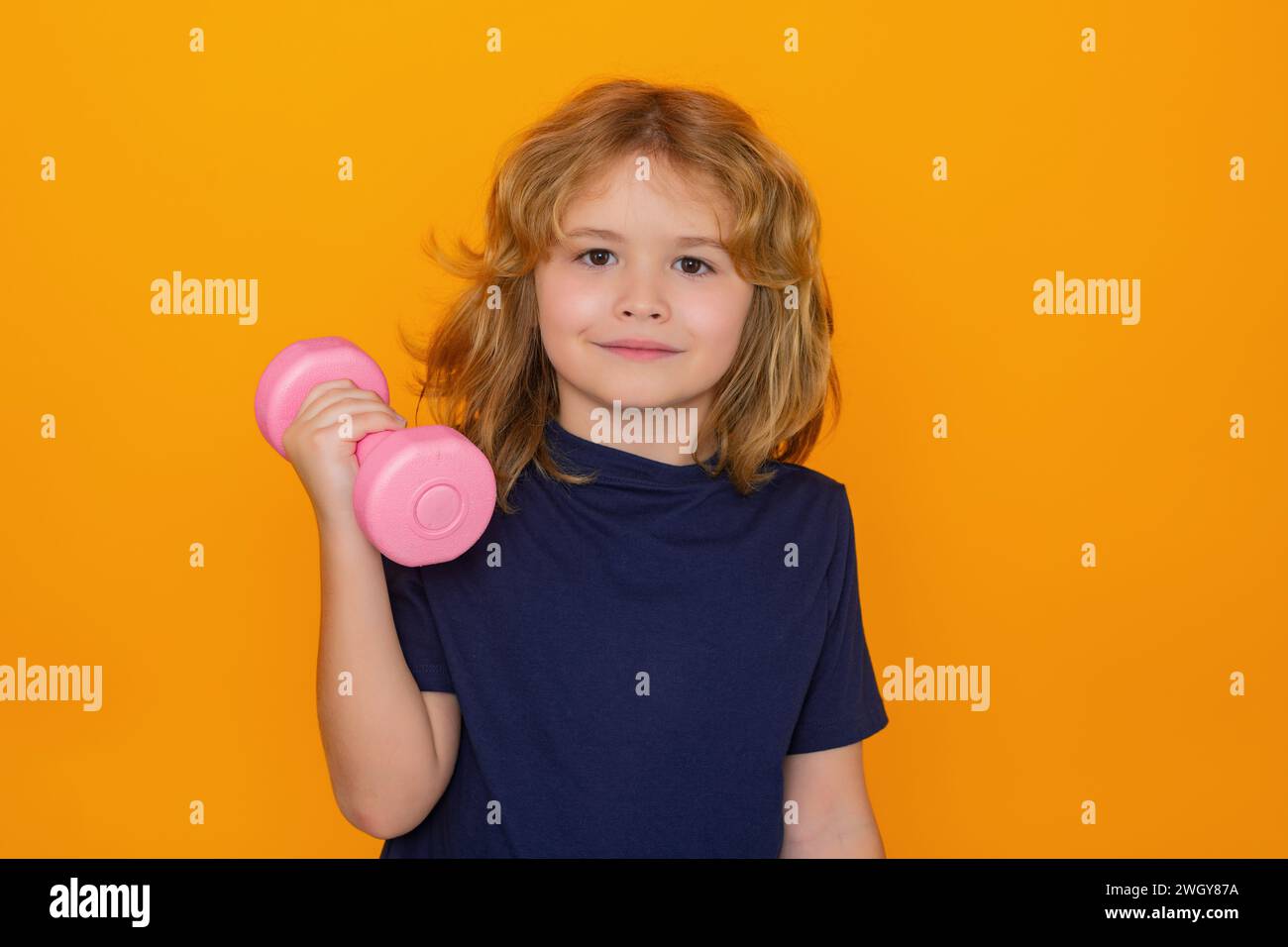 Portrait of sporty child with dumbbells, isolated on yellow studio background. Cute child boy ...