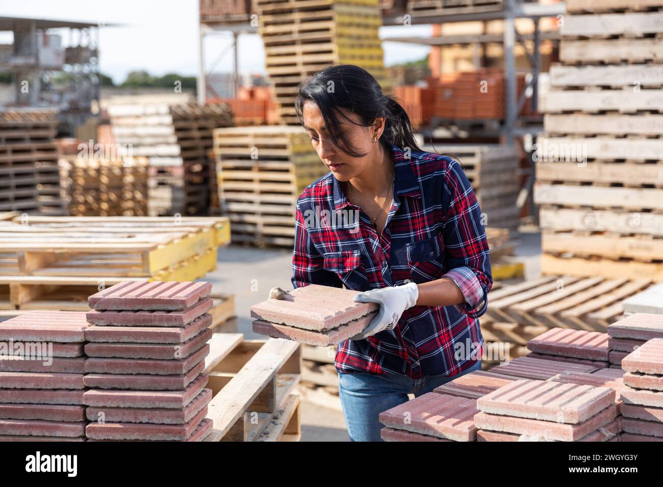 Woman places paving slabs on a pallet in building materials warehouse ...
