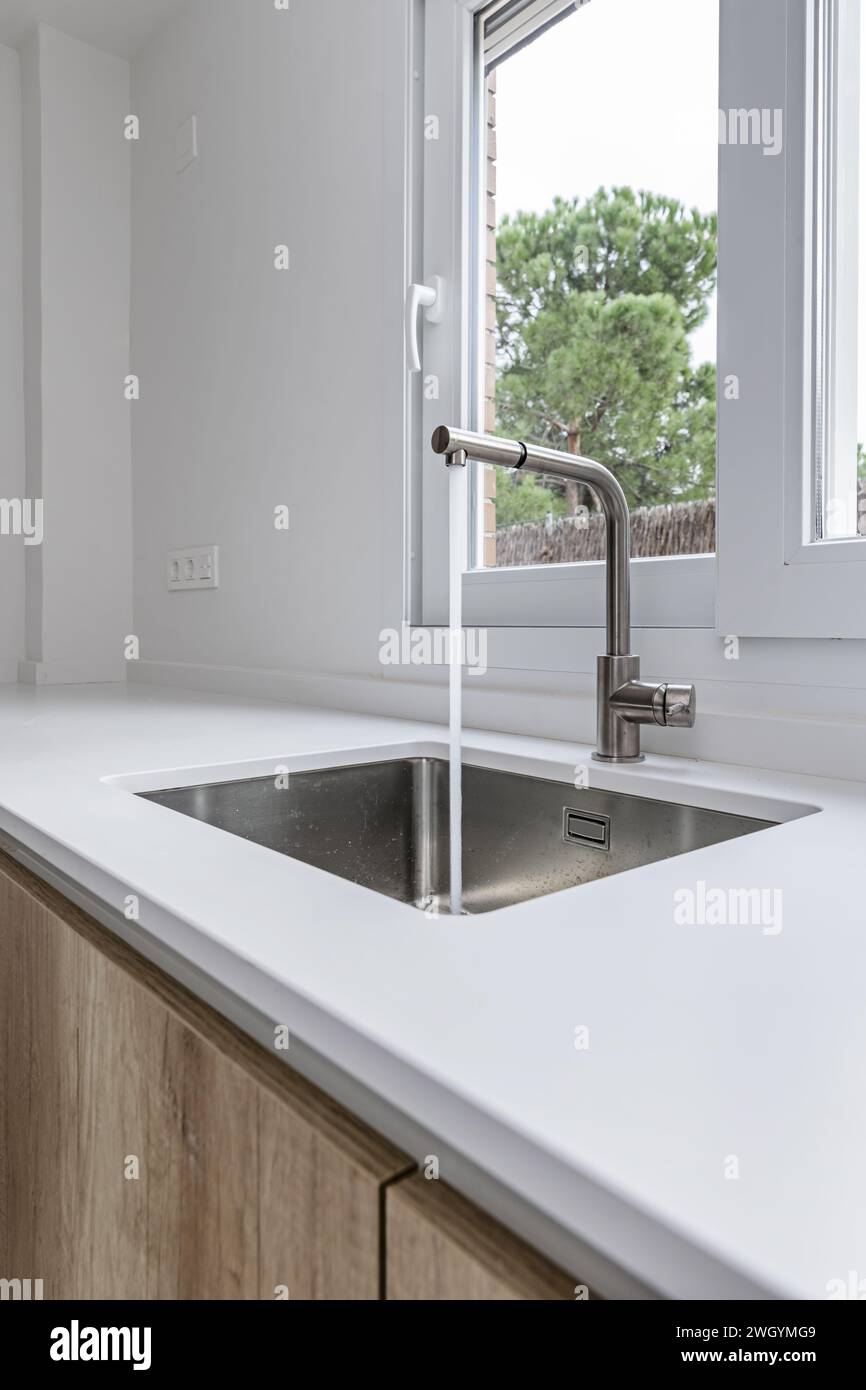 Open kitchen faucet pouring water into a stainless steel bucket built ...