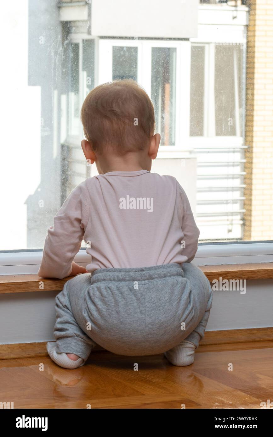 Baby looks out window, wants to play outside. Concept of wanting more ...