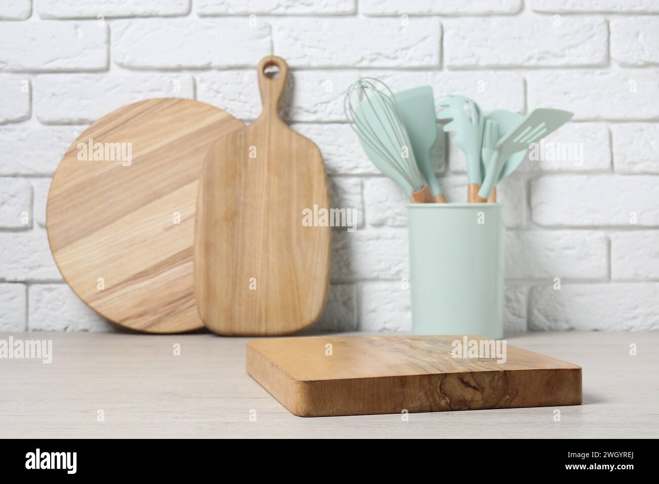 Different cutting boards and kitchen utensils in holder on light table ...