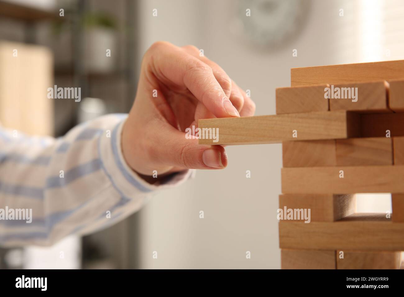 Playing Jenga. Woman removing wooden block from tower indoors, closeup ...