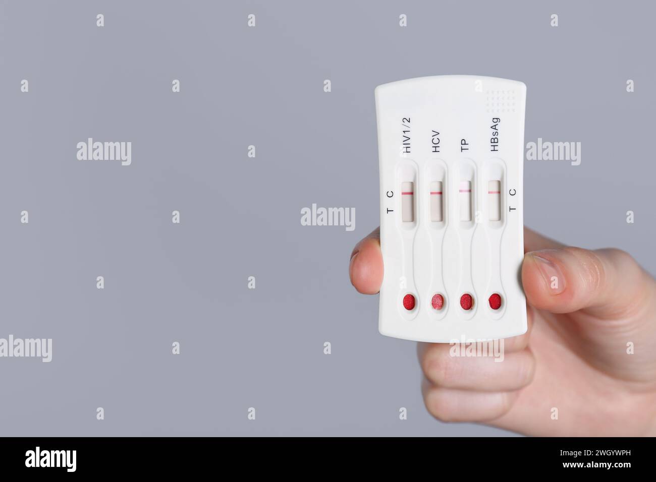 Woman holding disposable multi-infection express test on light grey ...