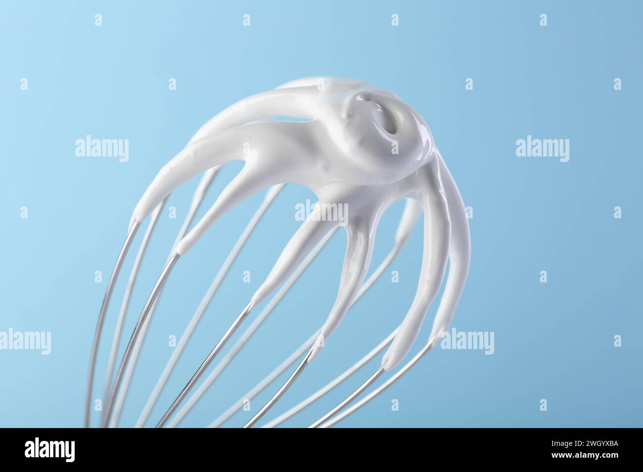 Whisk with whipped cream on light blue background, closeup Stock Photo ...