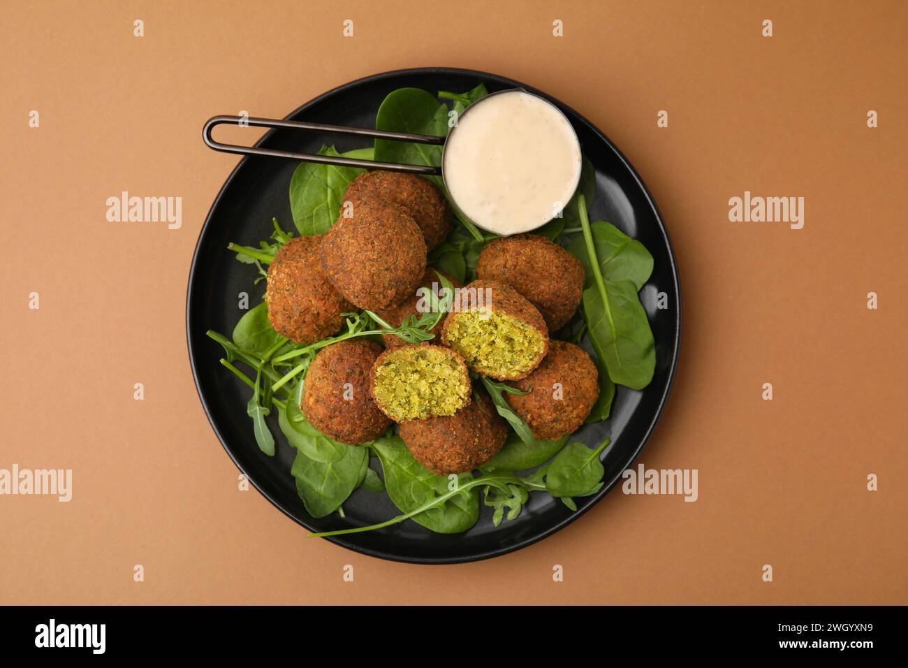 Delicious falafel balls, herbs and sauce on pale brown, top view Stock ...