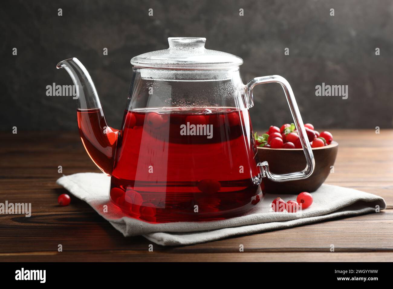 Tasty hot cranberry tea in teapot and fresh berries on wooden table ...