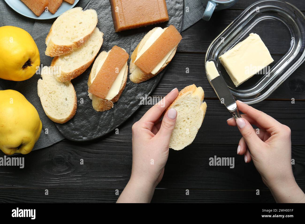 Making sandwich with quince paste. Woman spreading butter on bread at ...