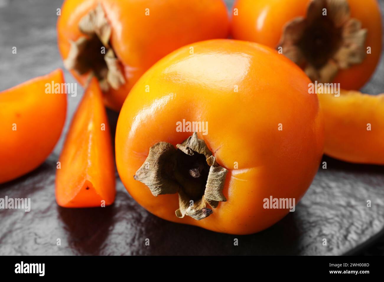 Delicious ripe persimmons on dark textured table, closeup Stock Photo ...