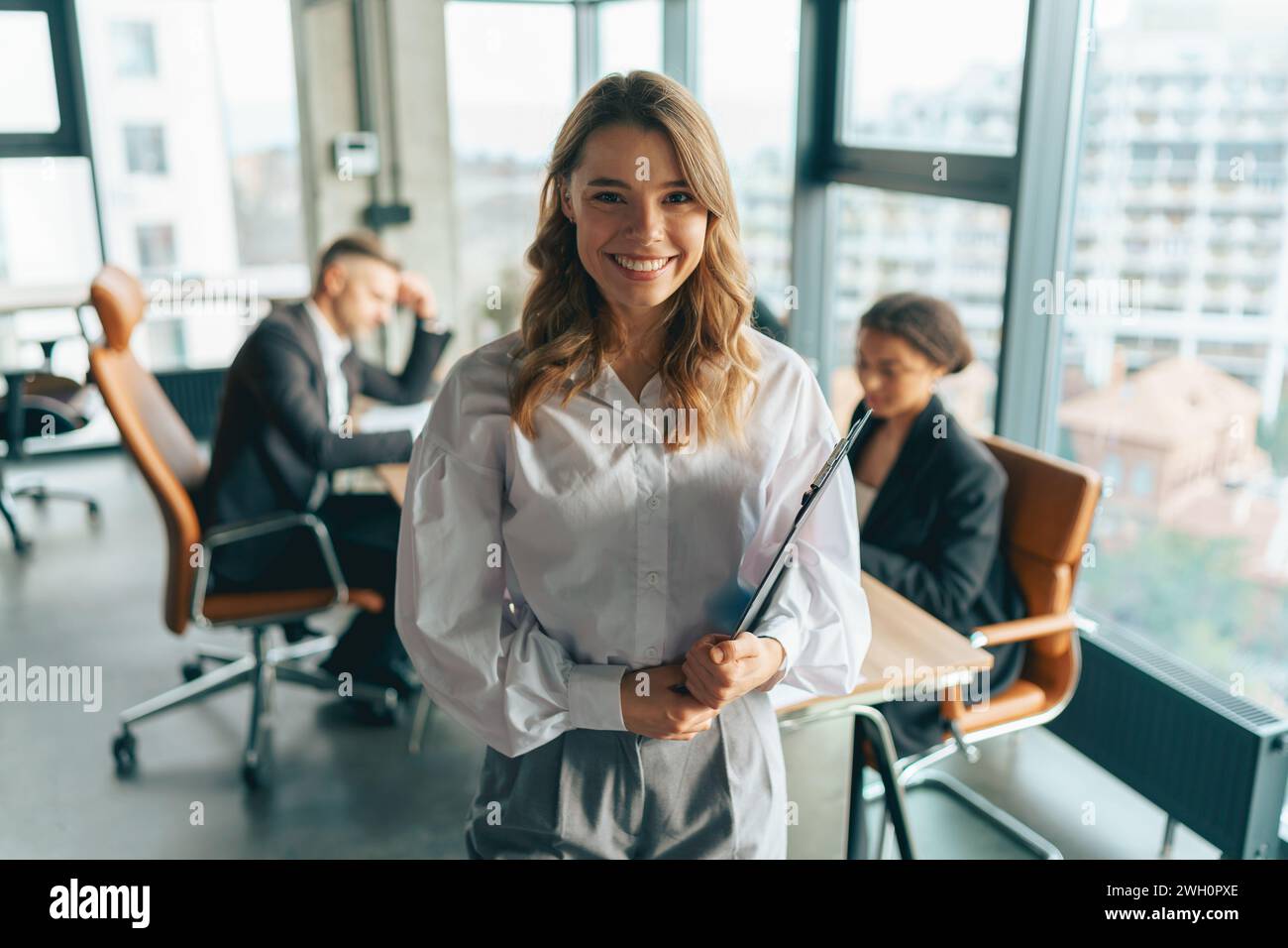 Smiling female accountant standing with documents in meeting room on ...