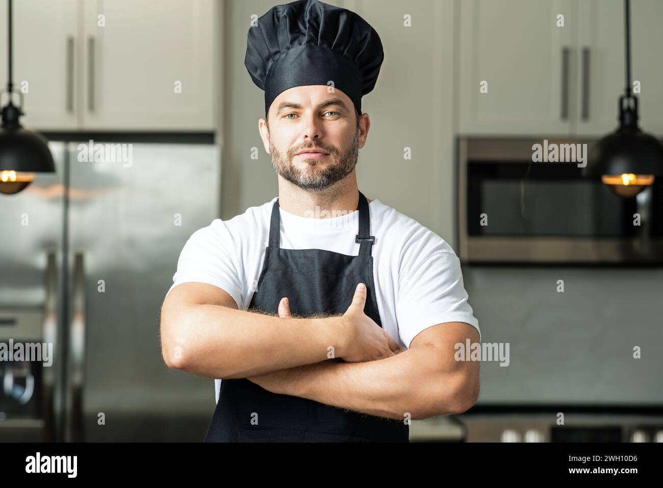 Portrait of chef man in a chef cap in the kitchen. Man wearing apron ...