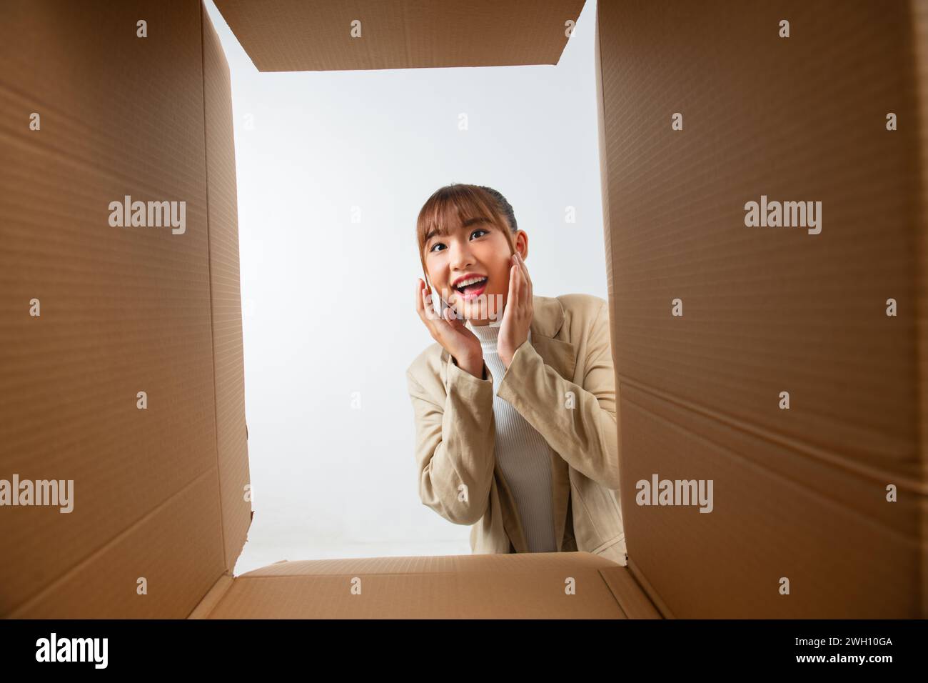 Young beautiful girl, opens and peeks into cardboard box. Bottom view ...