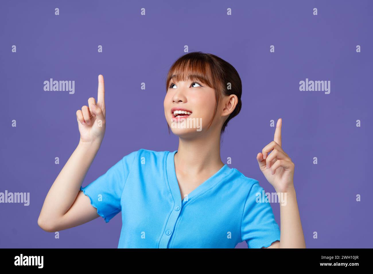 Cute asian woman raise hands up, showing promo, pointing fingers up ...