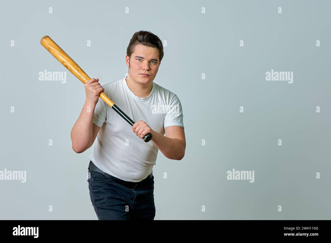 A man with a bat in his hands swings on a gray background Stock Photo ...