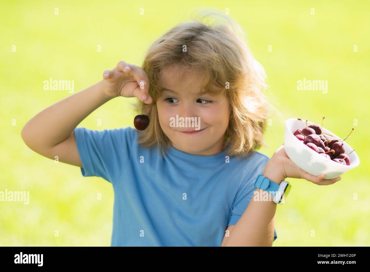Cherry and cute child. Child boy hold plate cherries in park. Cherry ...