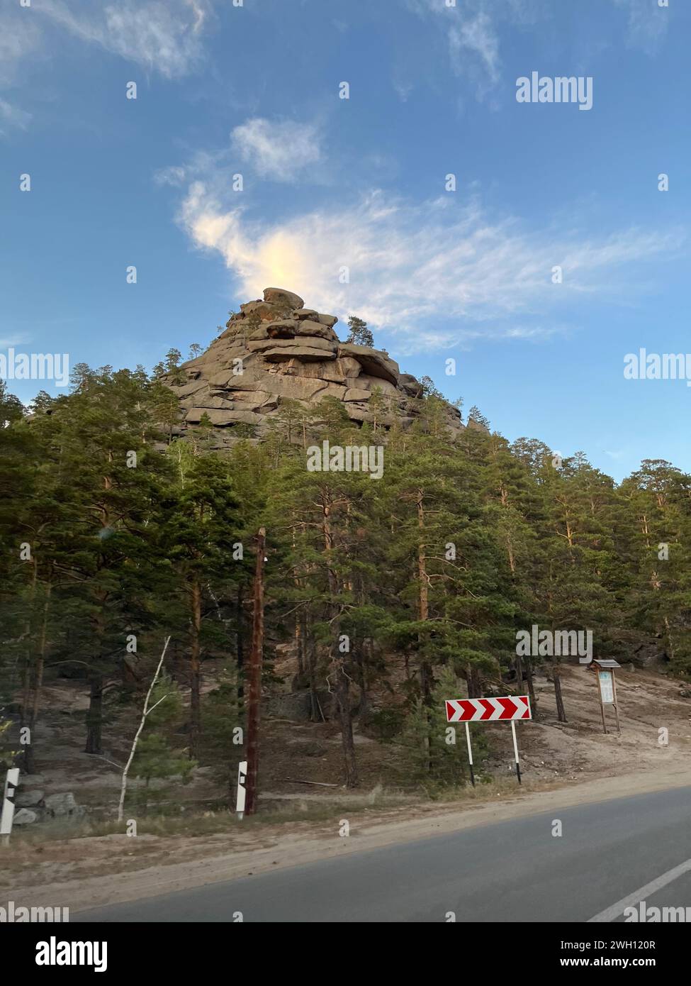 Towering rock formation emerges from the forest, commanding attention ...