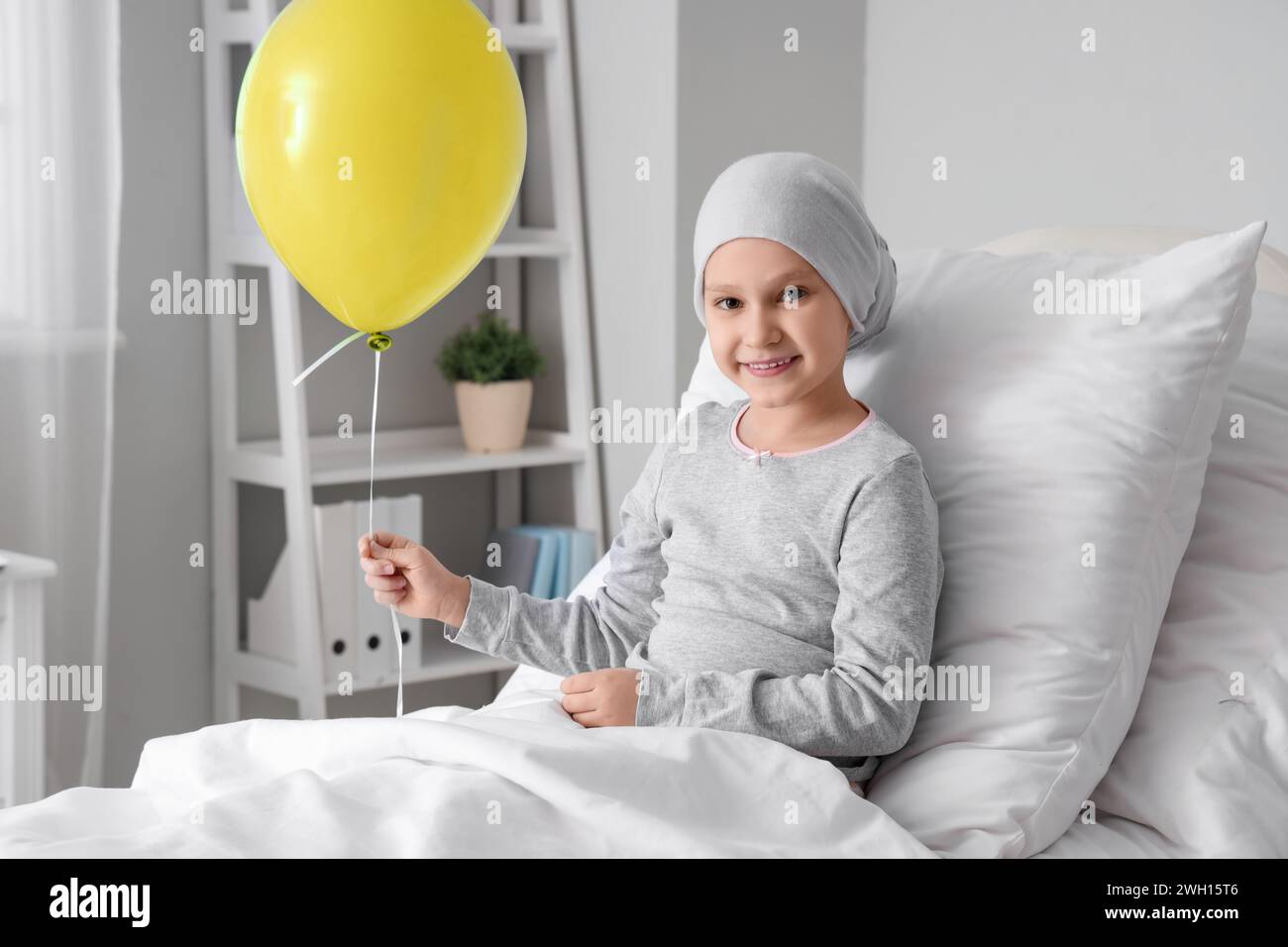 Little girl after chemotherapy with blue balloon lying in clinic ...