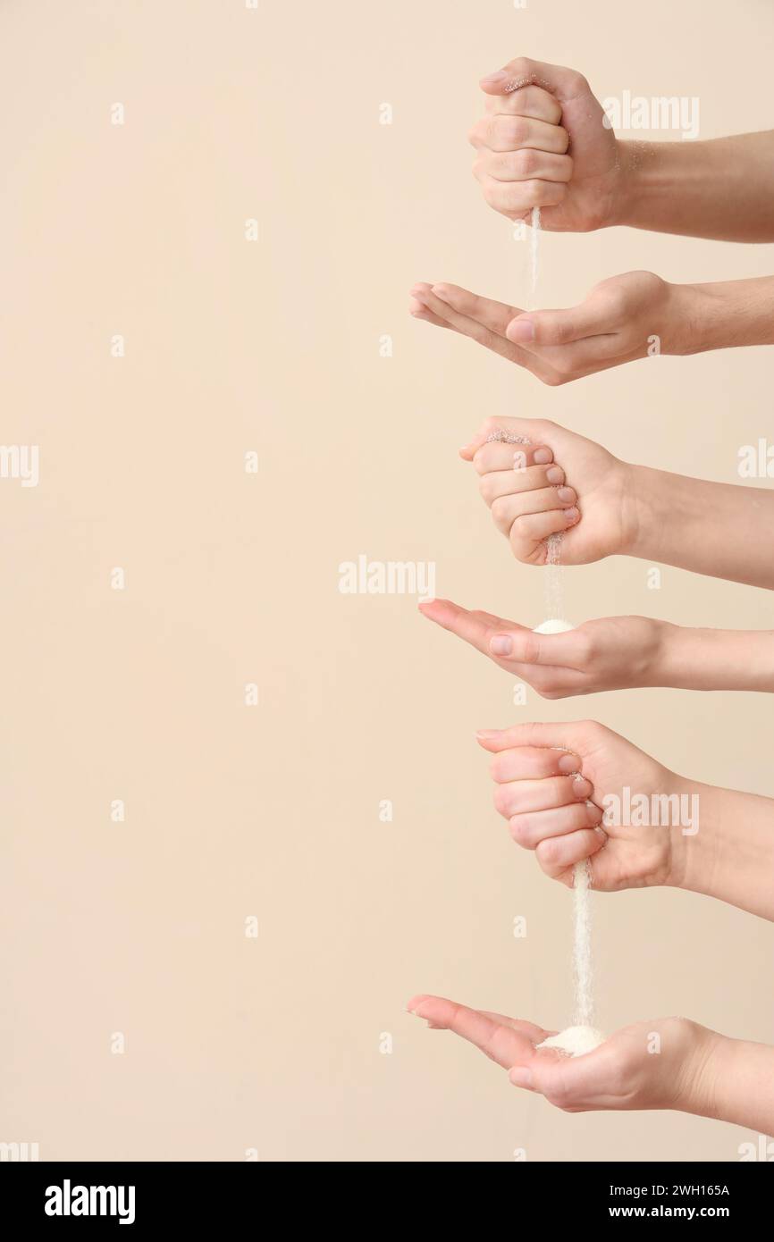 Many hands with pouring sand on beige background. Time concept Stock ...