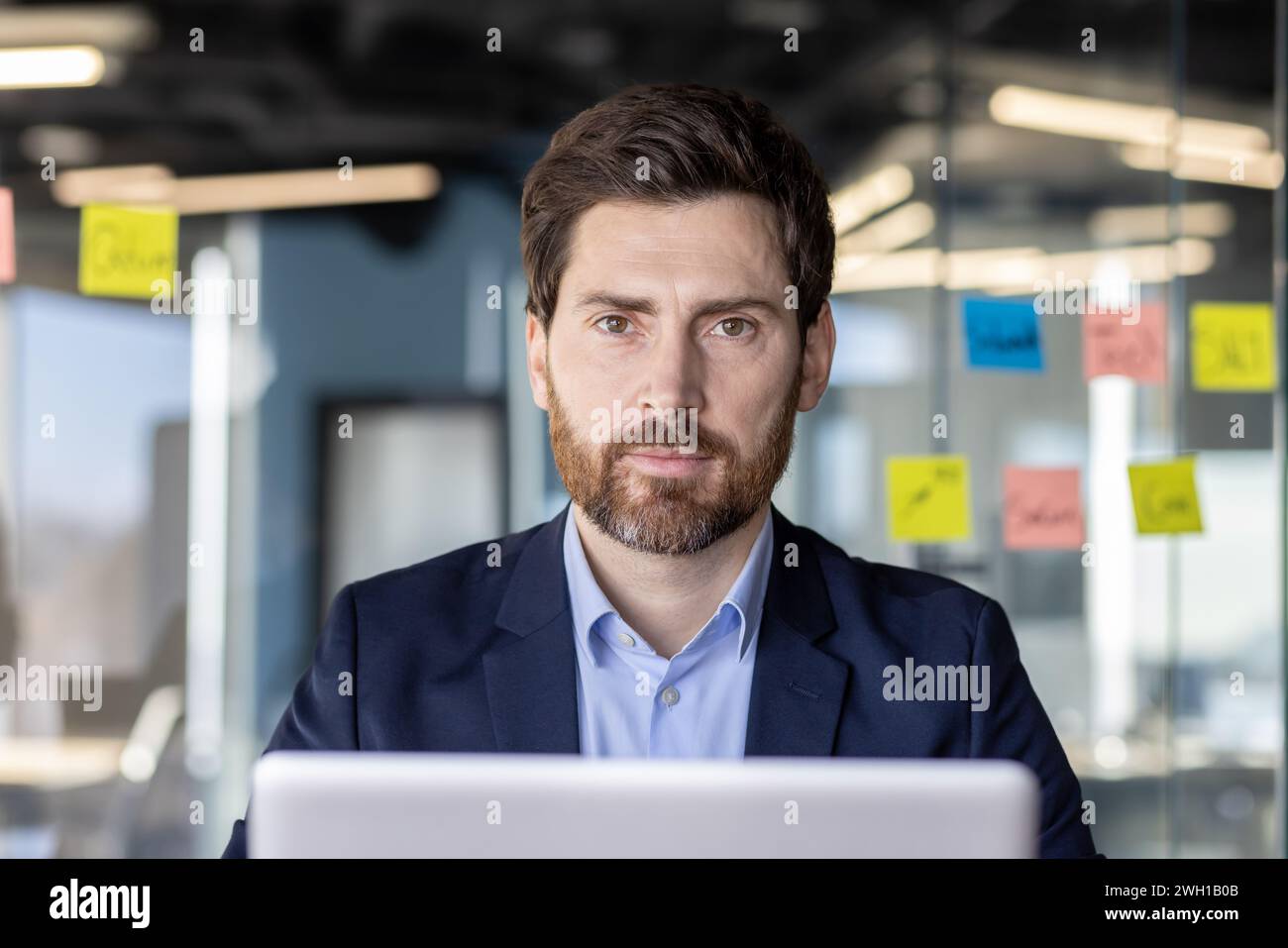 Mature businessman works at his laptop in a modern office setup ...