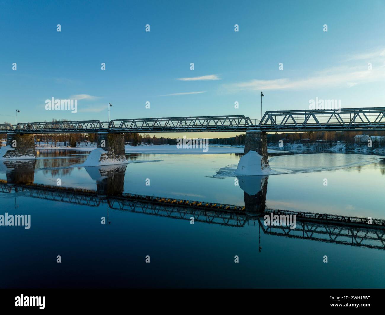 A train bridge over a smooth river in winter Stock Photo - Alamy