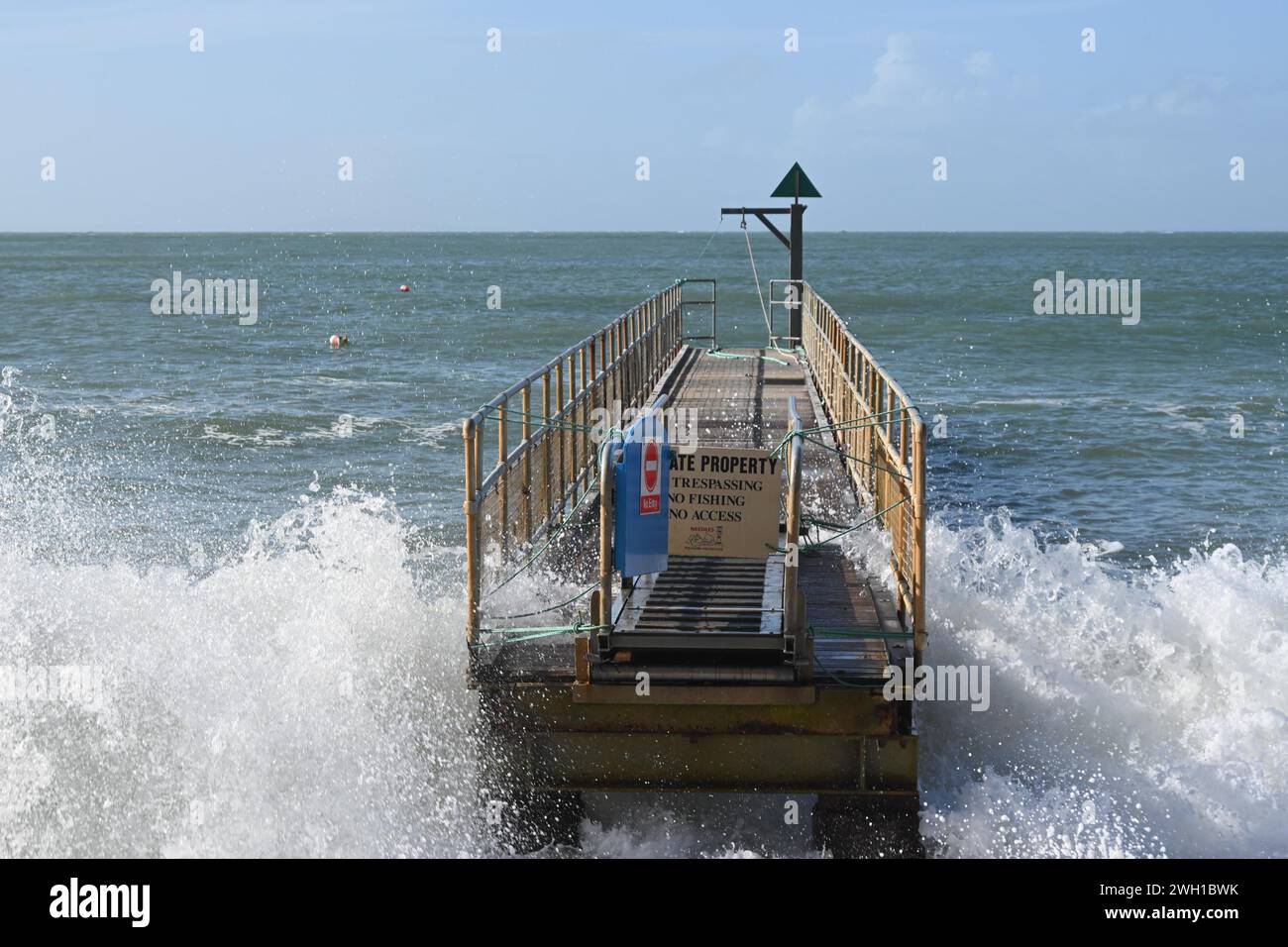 Waves crashing onto a stairless pier as the sea surges over it Stock ...